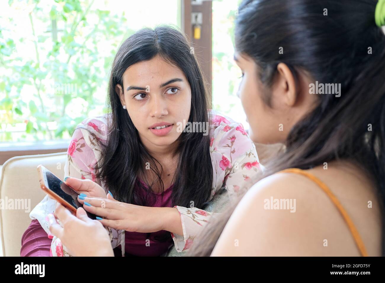 Closeup of two girls sitting on the couch and talking Stock Photo - Alamy
