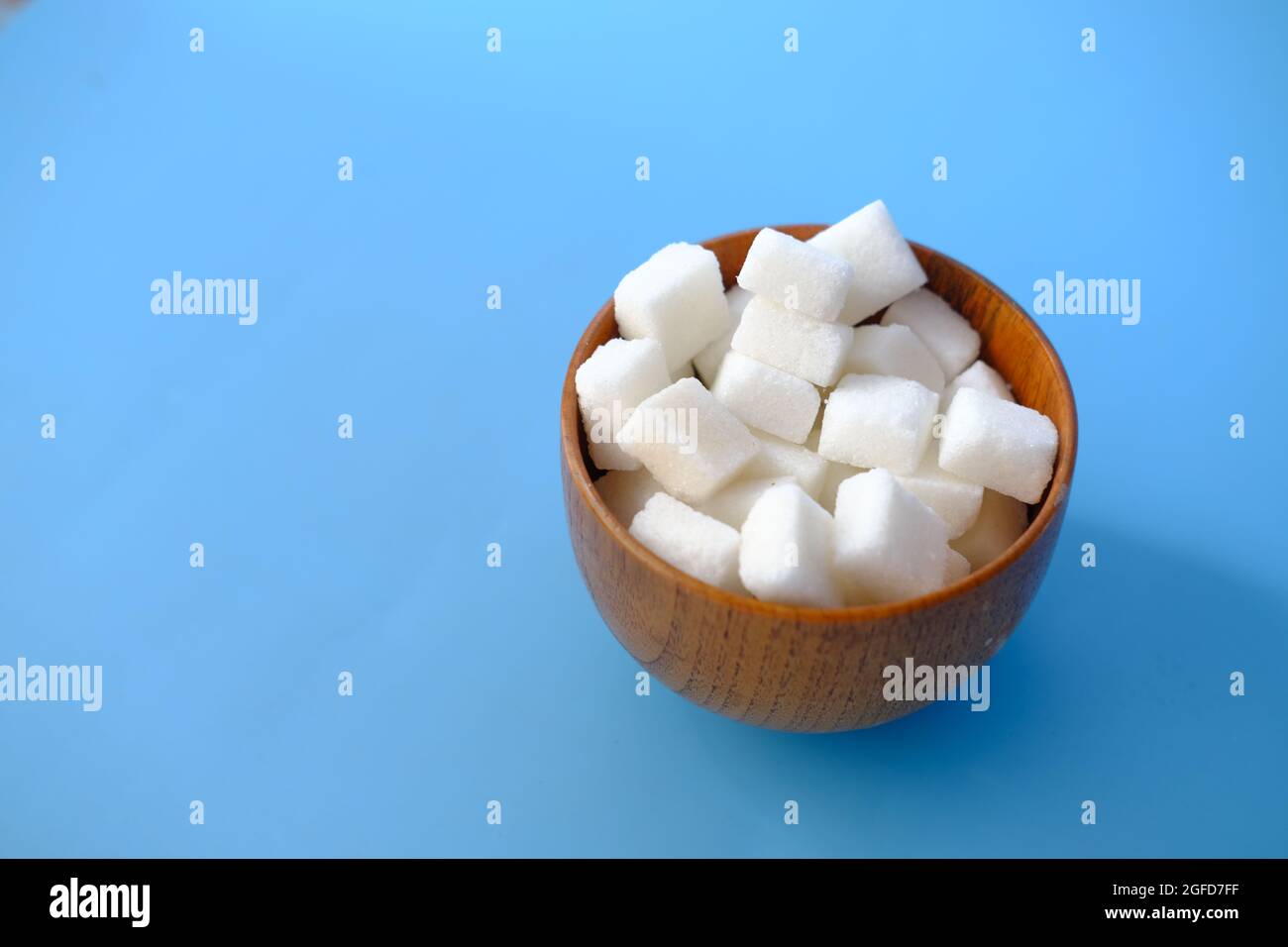 sugar cube in a wooden bowl on blue Stock Photo - Alamy