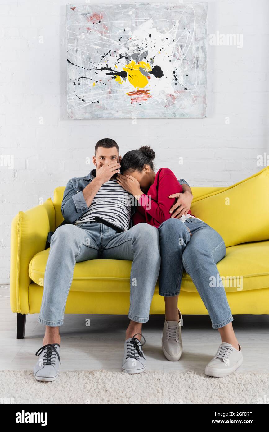 African american woman hiding near scared boyfriend and remote ...