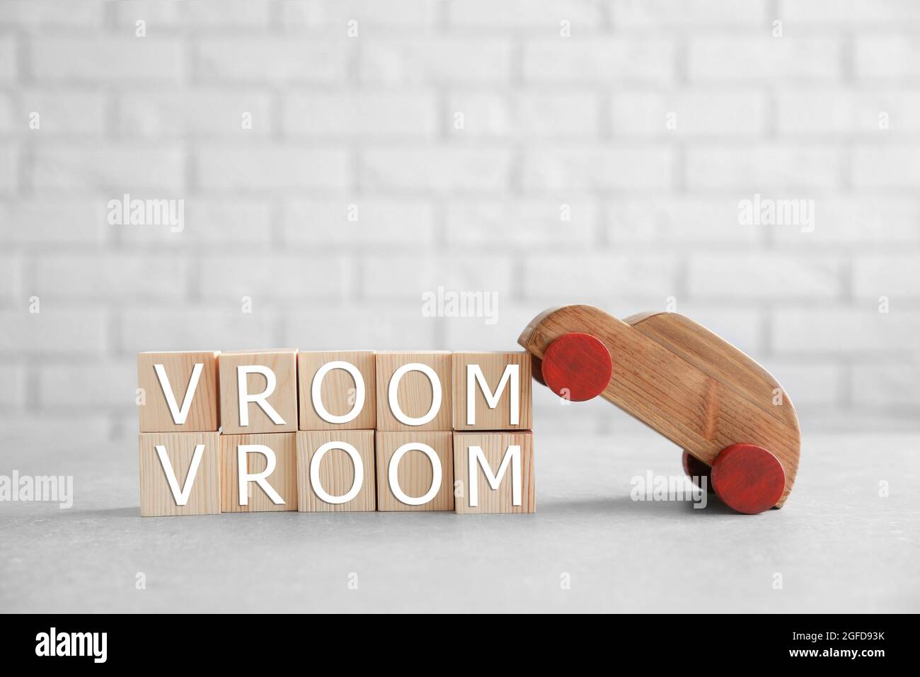 Cubes with words VROOM VROOM and toy car on brick wall background Stock ...