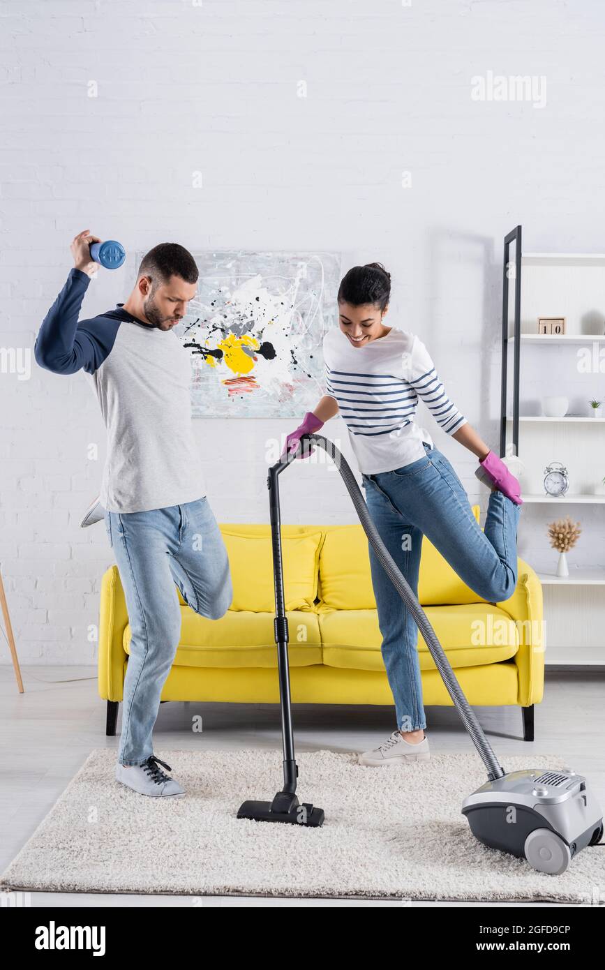 Young interracial couple dancing while cleaning living room Stock Photo ...