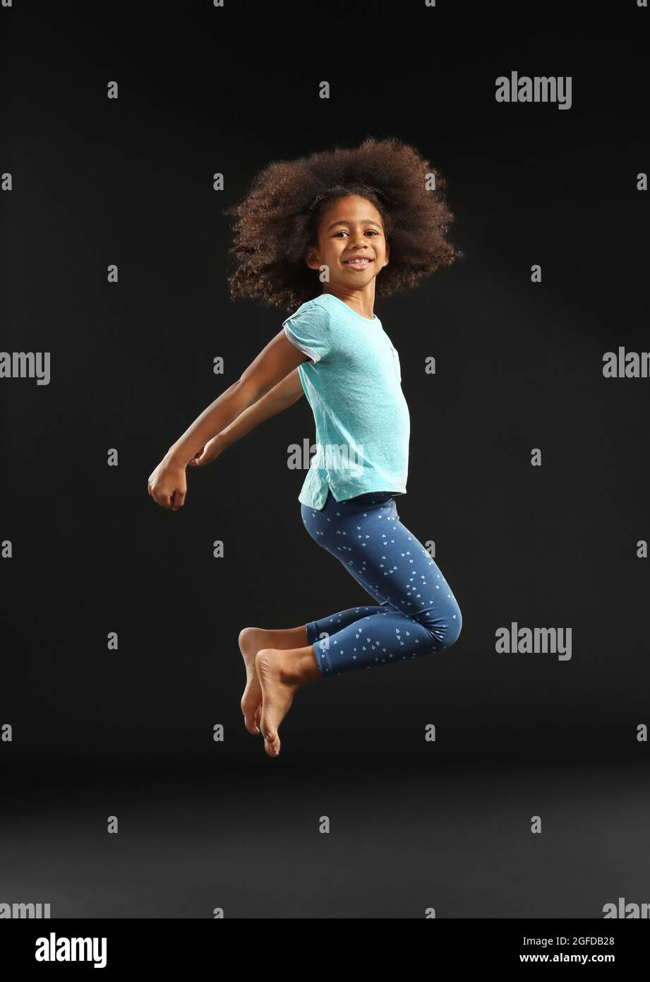 Happy African girl jumping on black background Stock Photo - Alamy