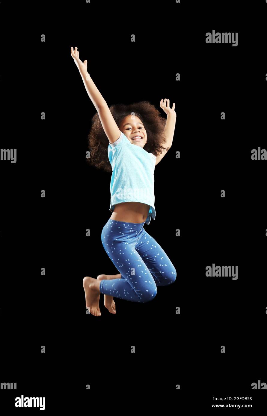 Happy African girl jumping on black background Stock Photo - Alamy