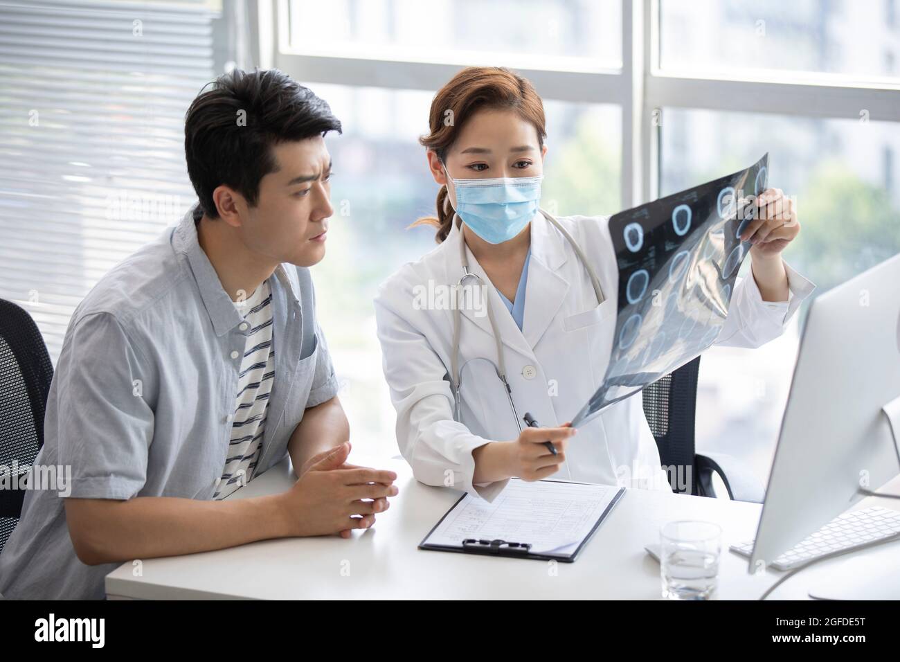 Doctor discussing X-ray image with patient Stock Photo - Alamy