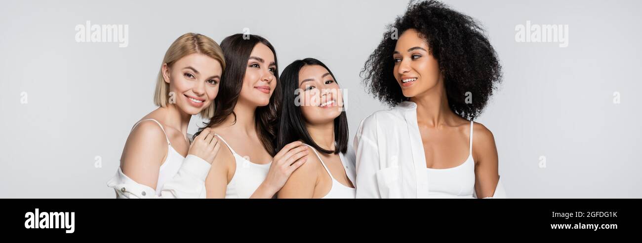 group of joyful multiethnic models smiling and posing isolated on grey ...