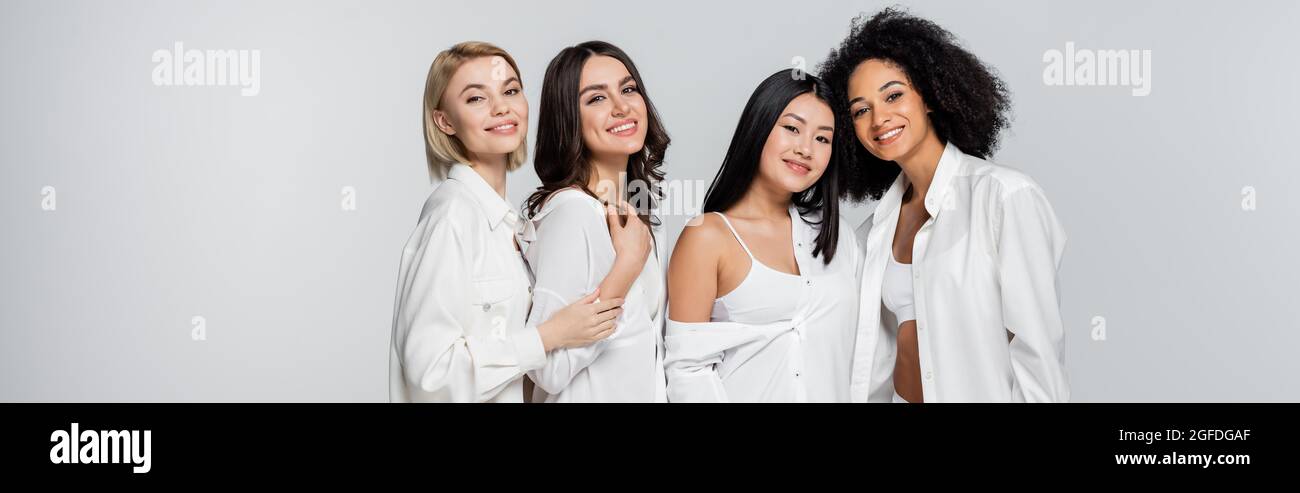 group of cheerful multiethnic models smiling isolated on grey, banner ...