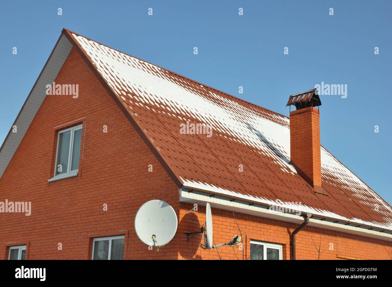 A close-up of a house from red brick with two satellite dish antennas ...