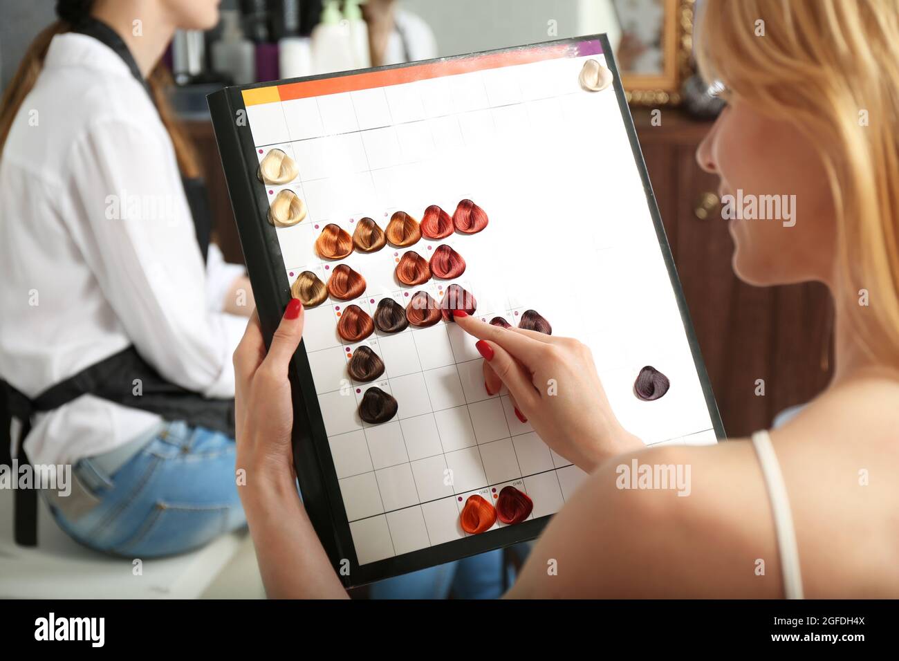 Beautiful young woman choosing color hair from palette at hairdressing ...