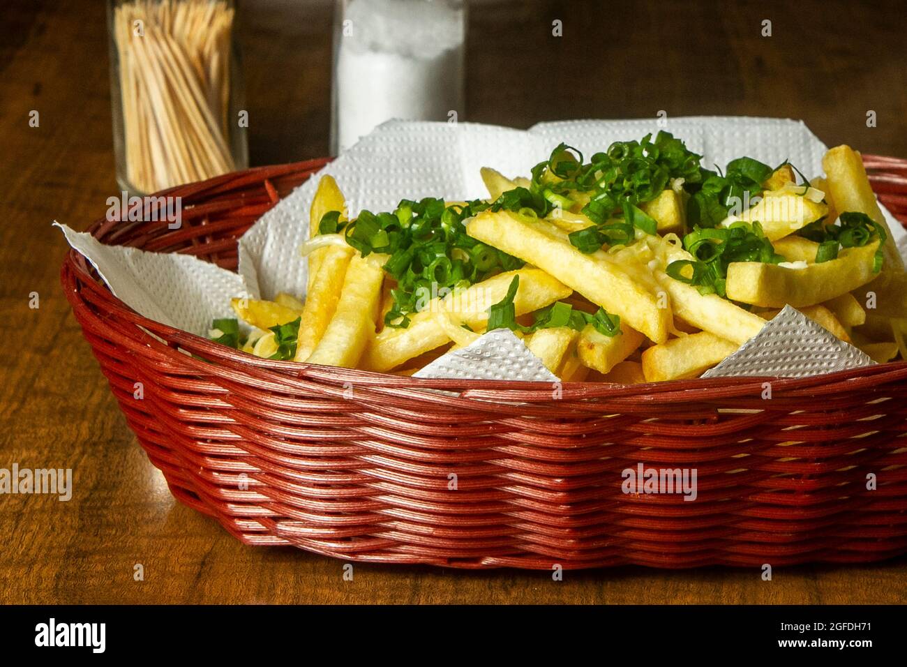 Brown wicker basket with french fries, lightly melted grated cheese and ...