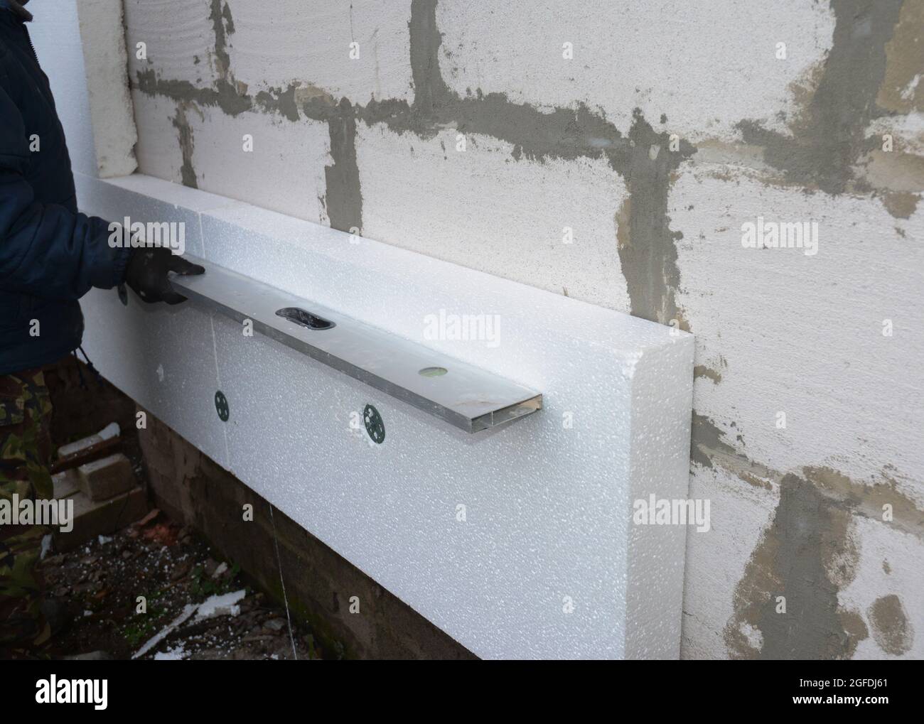 A building contractor installing external wall polystyrene boards ...