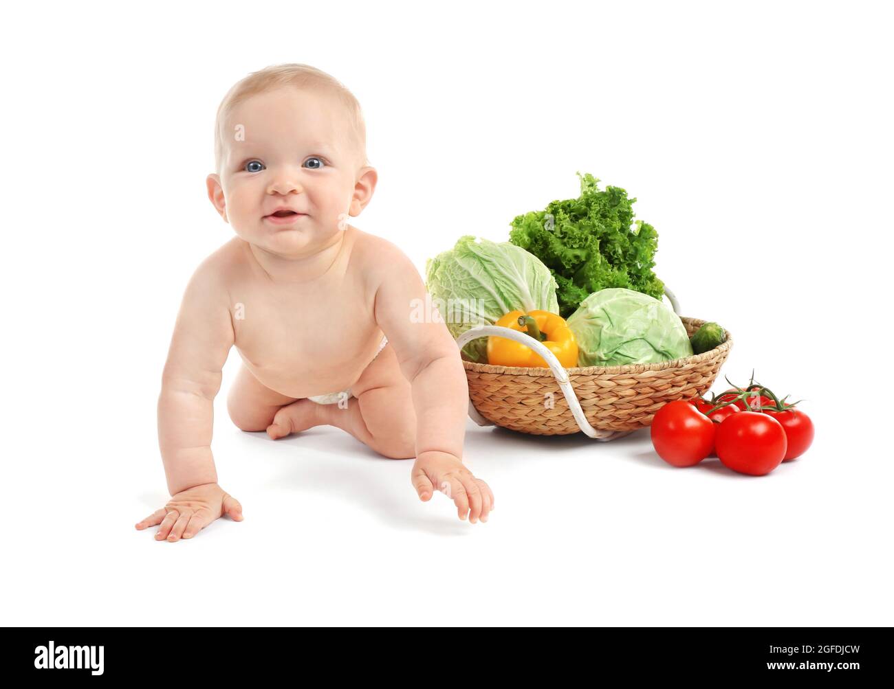 Cute baby and fresh vegetables in wicker basket on white background ...