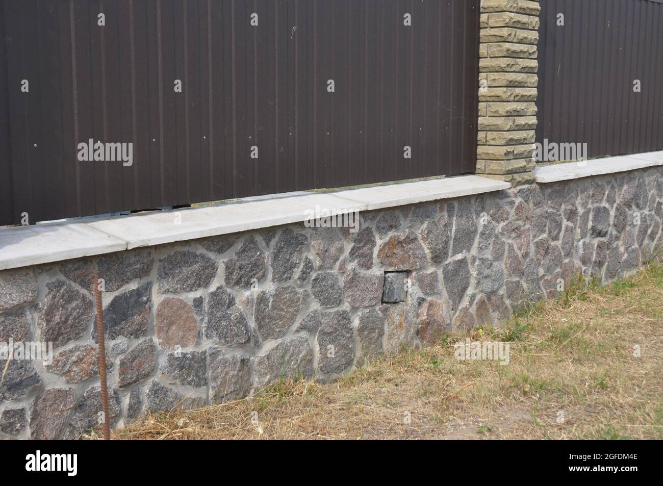 A close-up of a brown metal corrugated fence installed on a wild ...