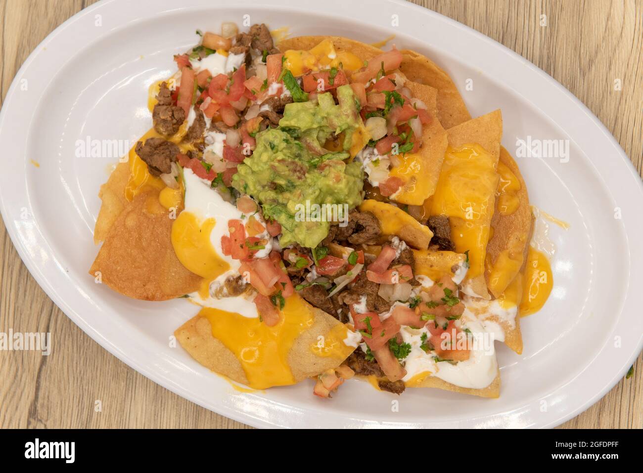 Overhead view of hearty plate of nachos smothered with melted cheese ...