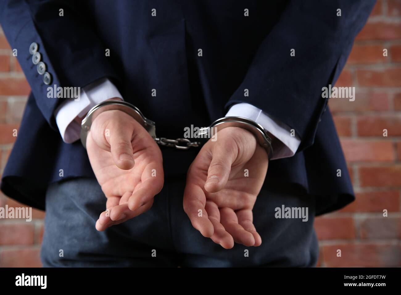 Man in handcuffs on brick wall background Stock Photo - Alamy