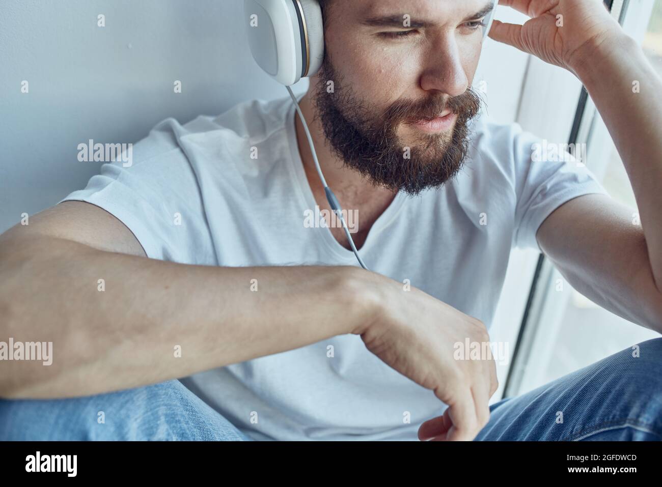 Man sitting near the window in headphones listening to music on ...
