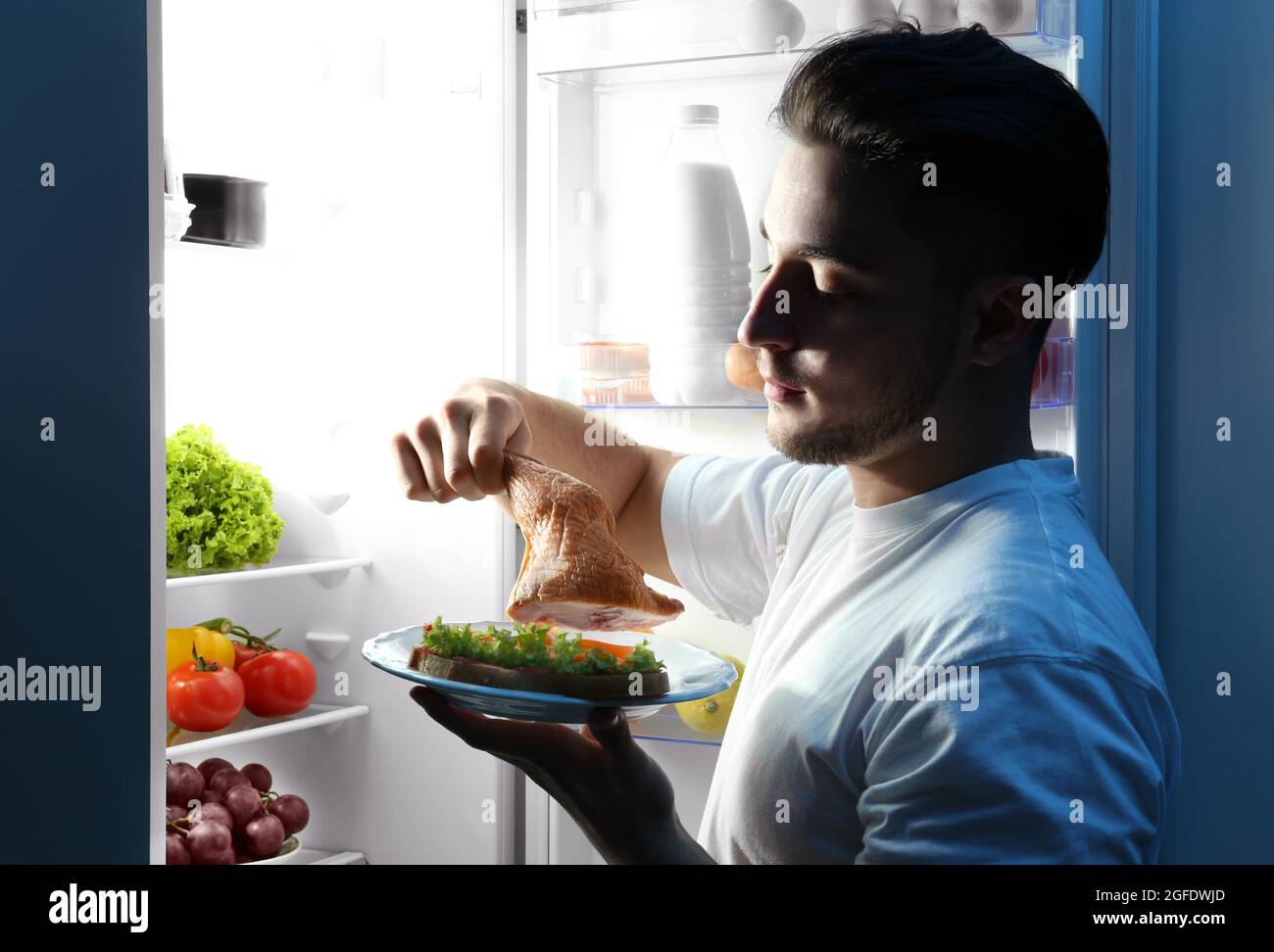 Handsome man eating chicken in kitchen. Unhealthy food concept Stock ...