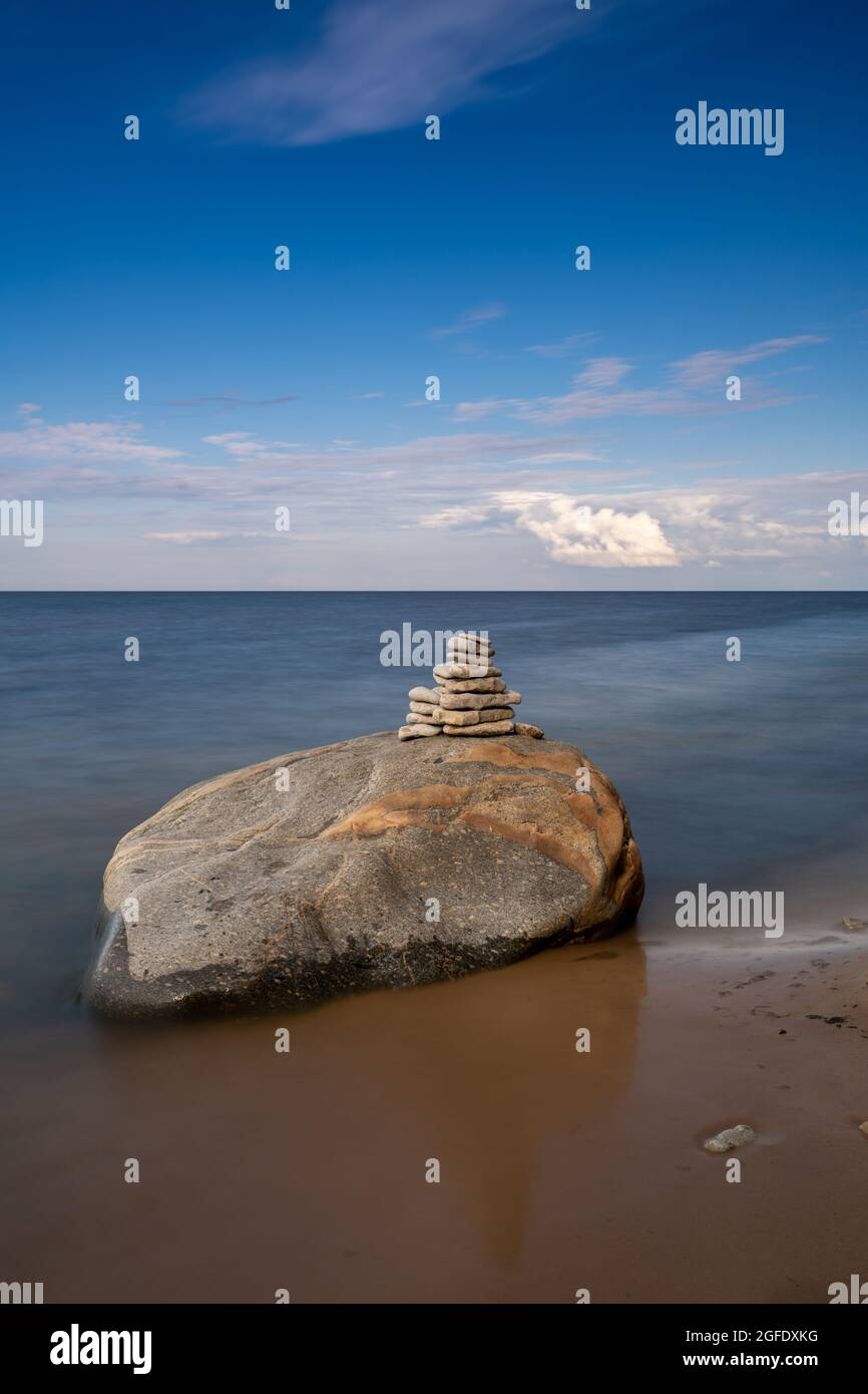 A meditative rock cairn on top of a boulder with long exposure ocean ...