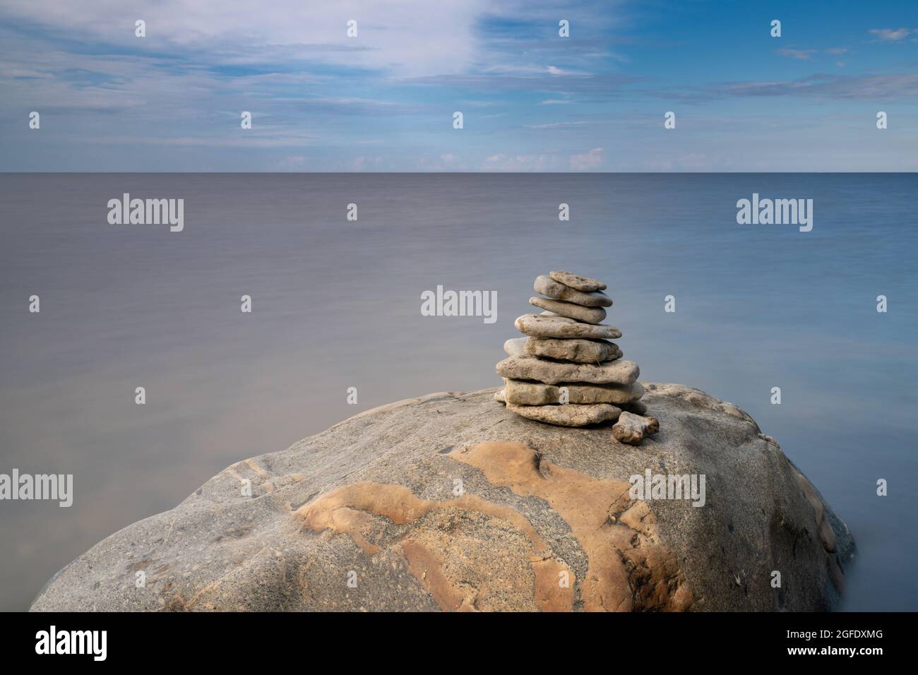A meditative rock cairn on top of a boulder with long exposure ocean ...