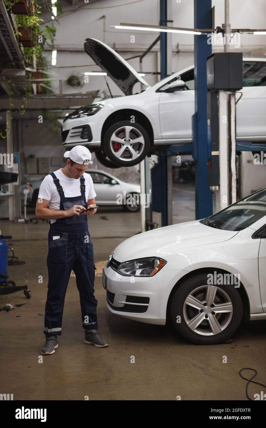 Vertical full shot of a professional car mechanic working at the ...