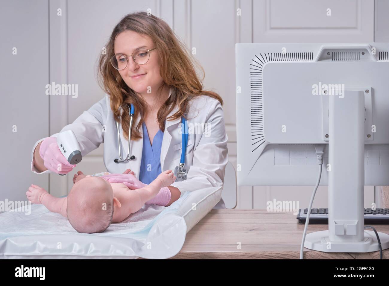 Doctor checks the temperature of the newborn baby with a thermometer. A ...