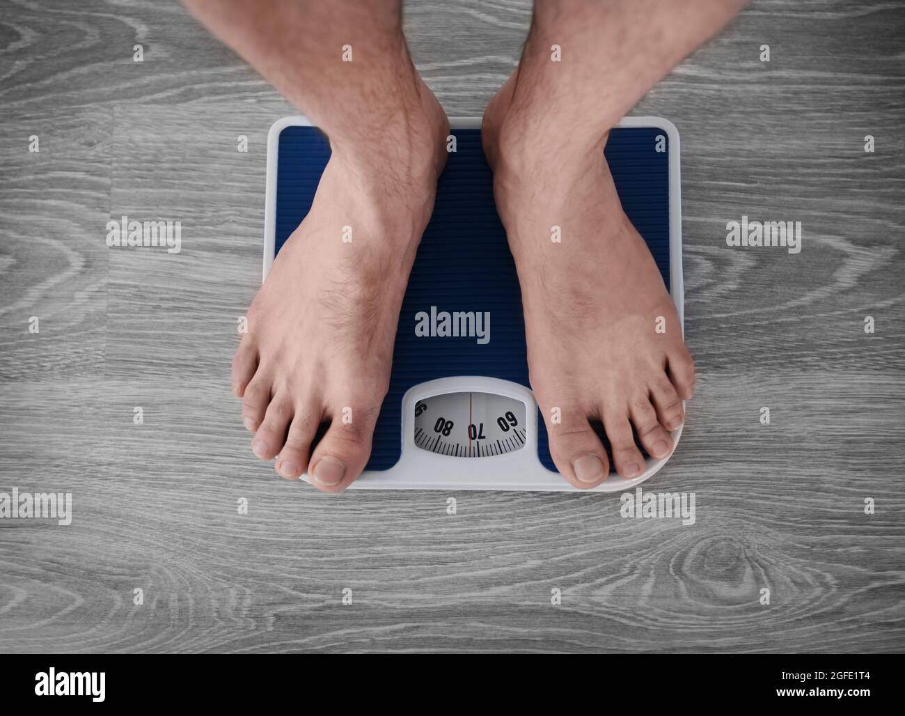Man standing on weight scale Stock Photo - Alamy