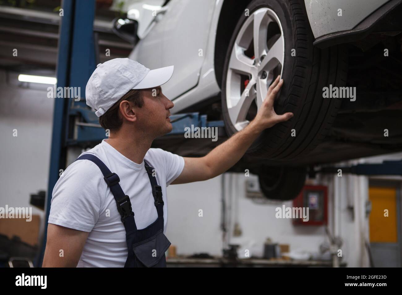 Male car service worker examining wheels of a car on the lift Stock ...