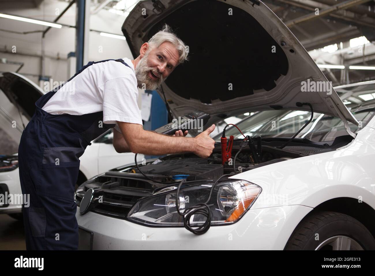 Bearded elderly car mechanic repairing automobile at service station ...
