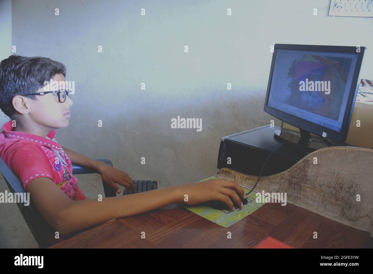 boy operating a computer using mouse and keyboard, He is looking at the ...