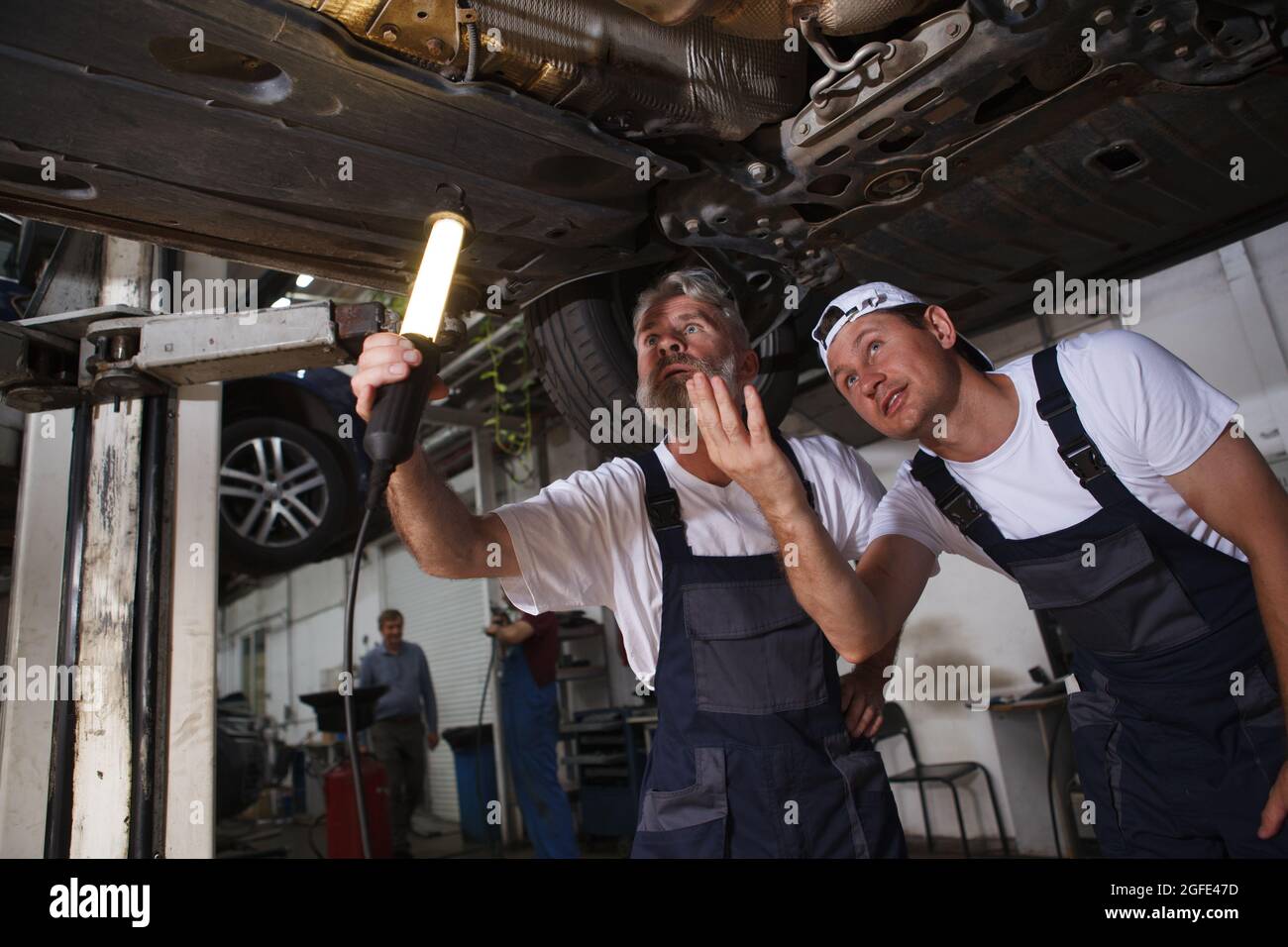 Low angle shot of two professional car repairment working on an ...