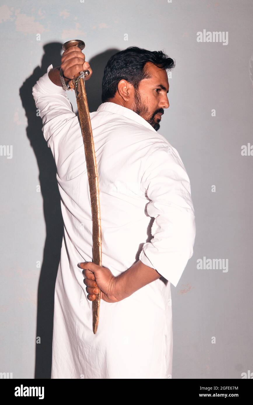 Kshatriya youth, wearing white kurta while shooting photo with sword ...