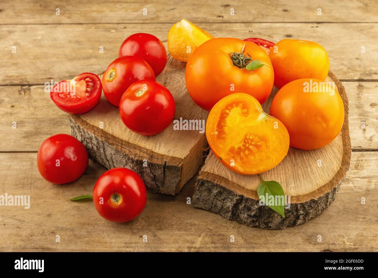 Assorted ripe tomatoes on a wooden stand. Fresh red and orange organic ...