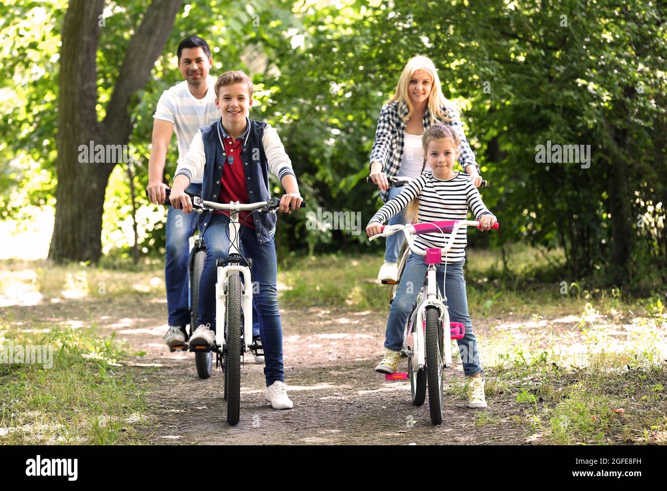 Happy family on bike ride in park Stock Photo - Alamy