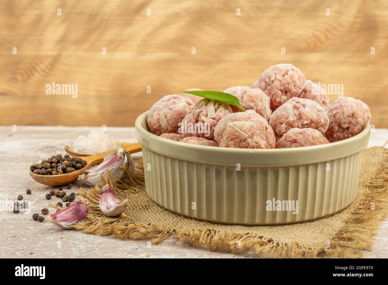 Frozen meatballs with spices, basil leaves, and garlic cloves in a ...