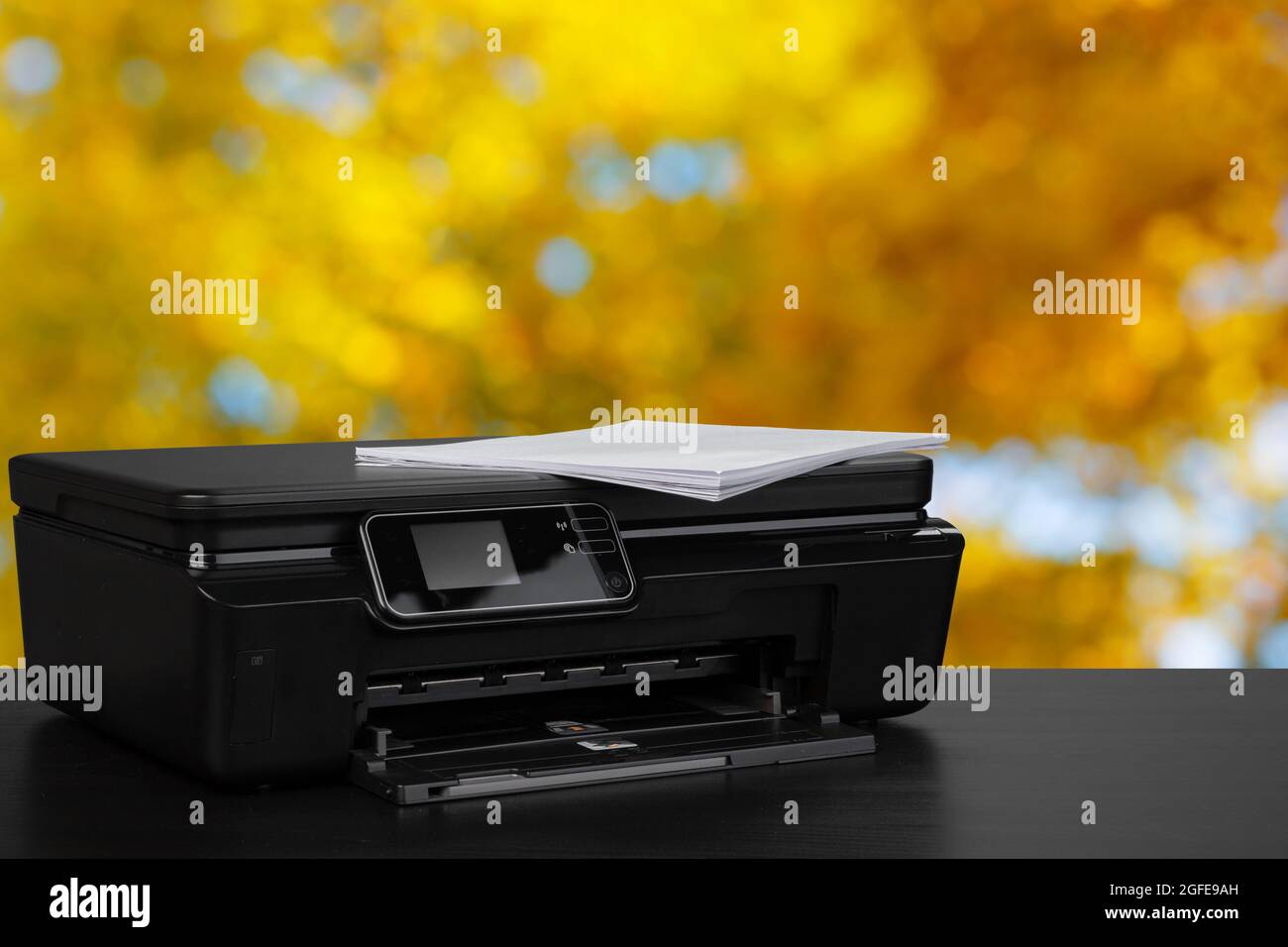 Compact laser printer on black desk against blurred background Stock ...