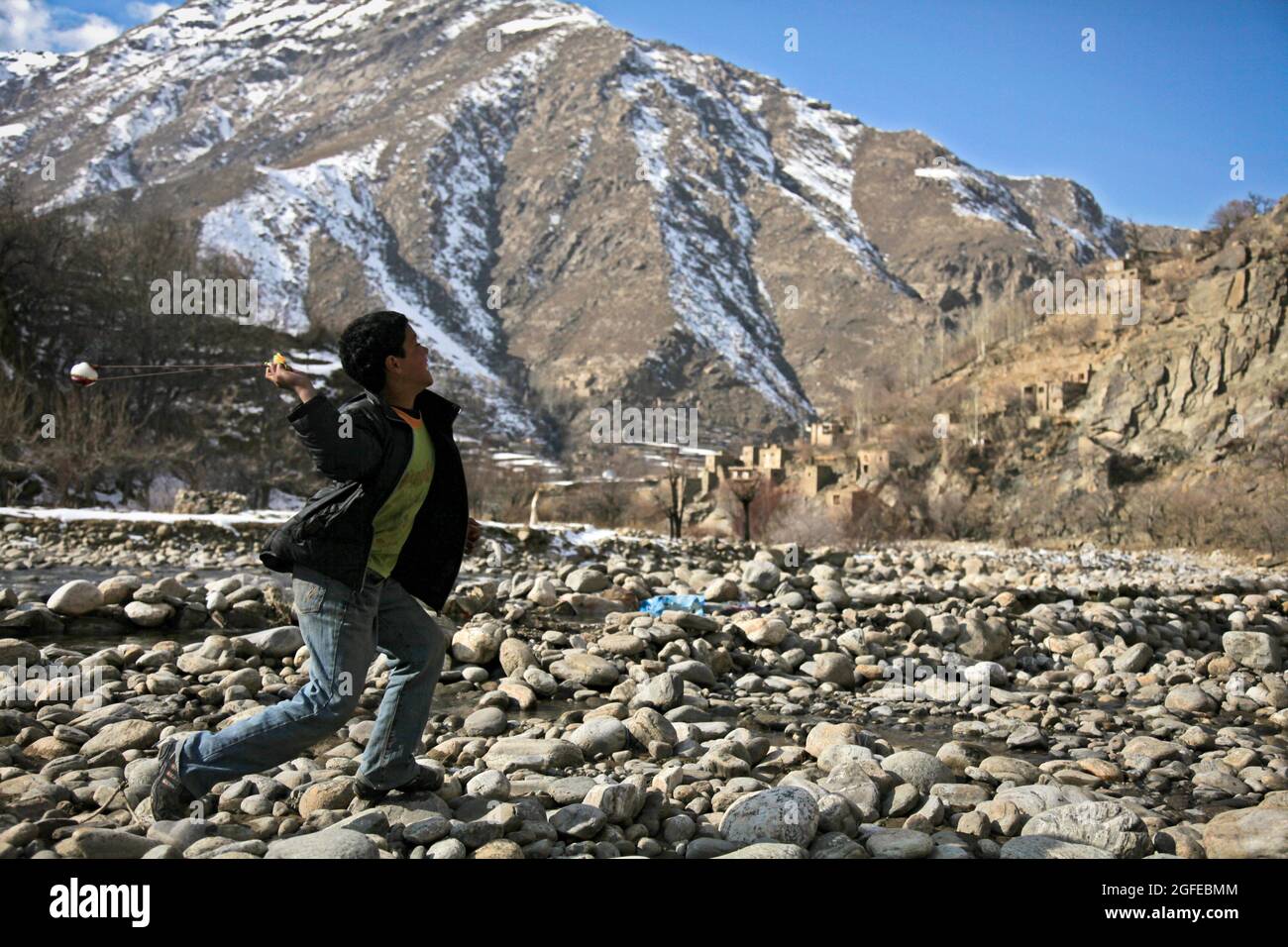 An Afghan child throws a snowball with a slingshot while playing next ...