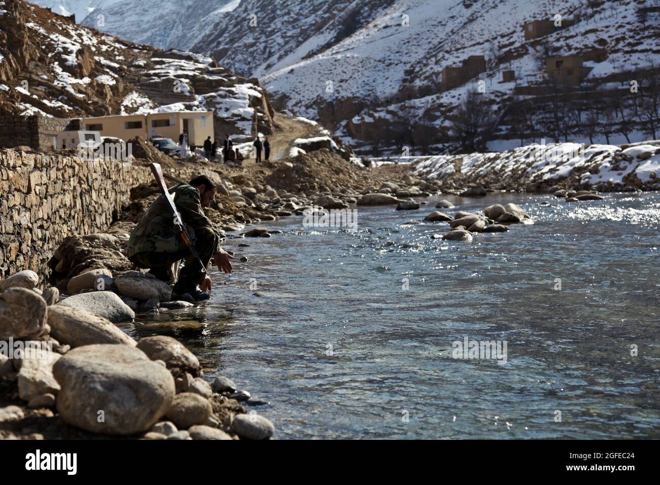 An Afghan security guard washes his hands on the river before eating ...