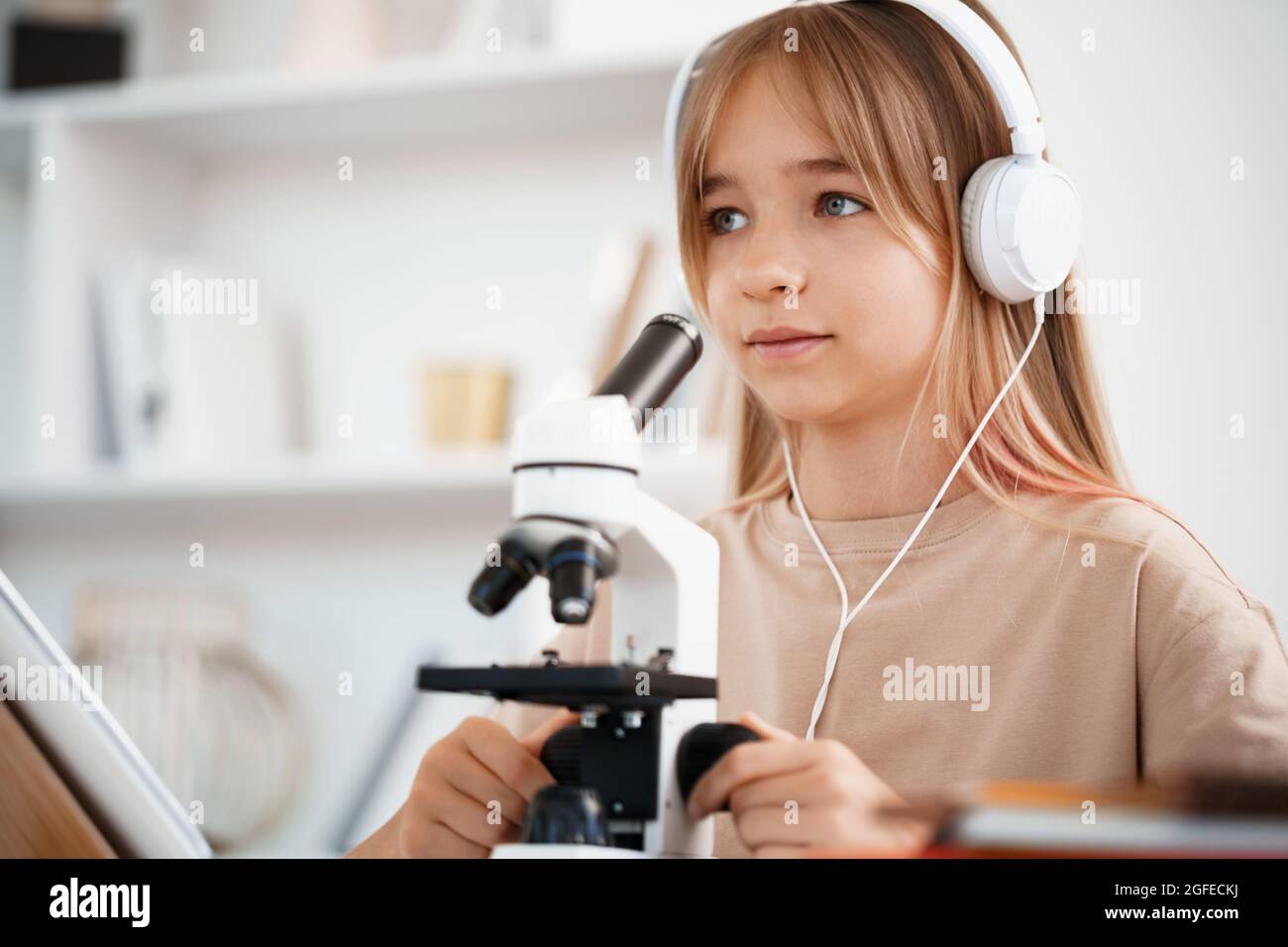 Young girl using microscope during online lesson education at home ...