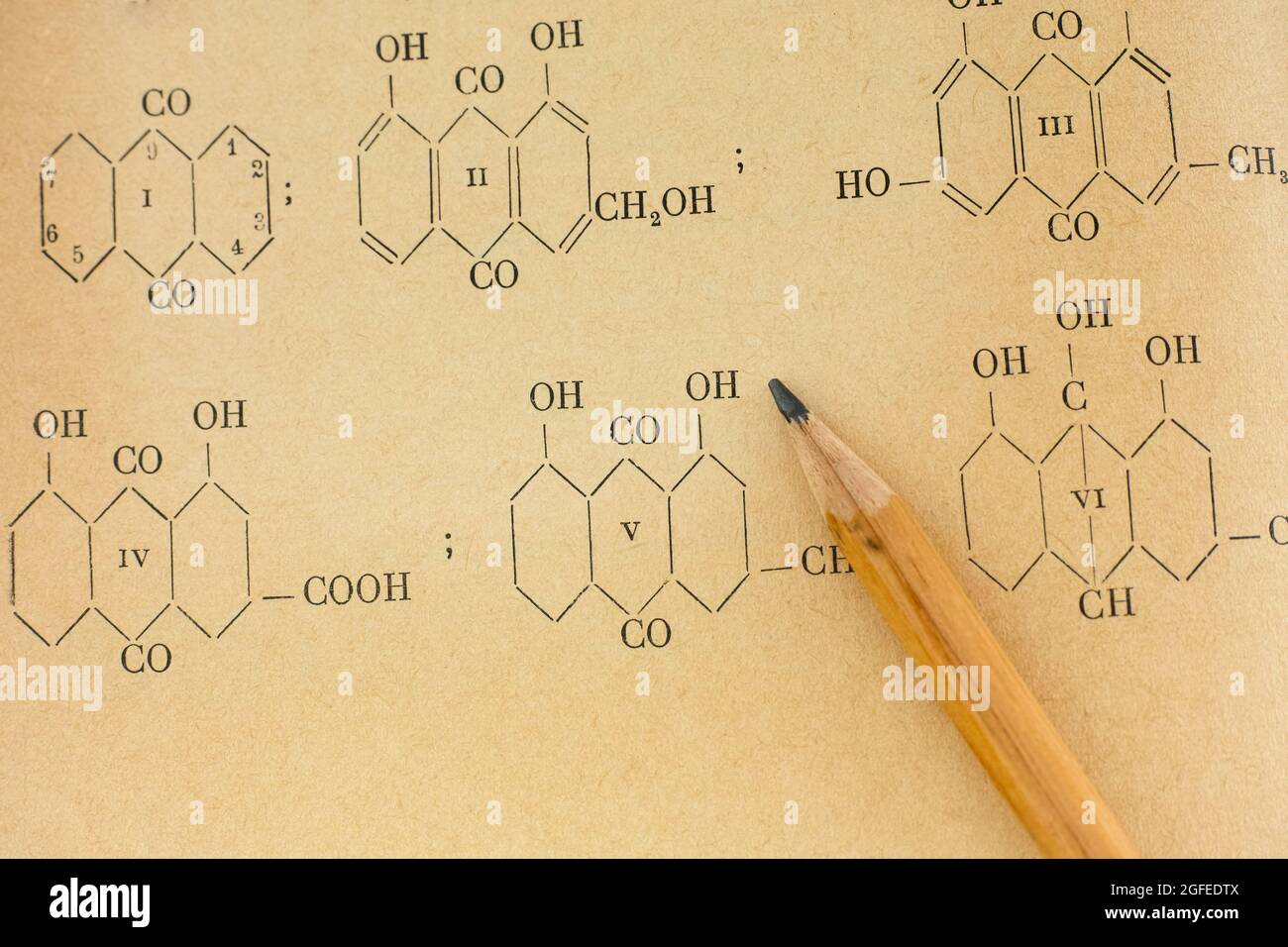 A Pencil lies on a page of old chemistry book with chemical formulas ...