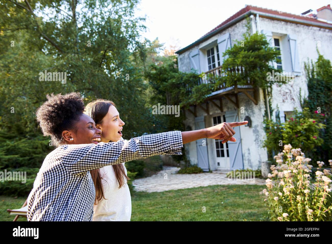 Young woman pointing at something in distance to her friend Stock Photo ...