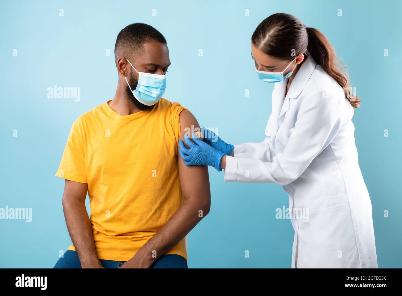 Doctor putting on band aid on African American male patient after ...