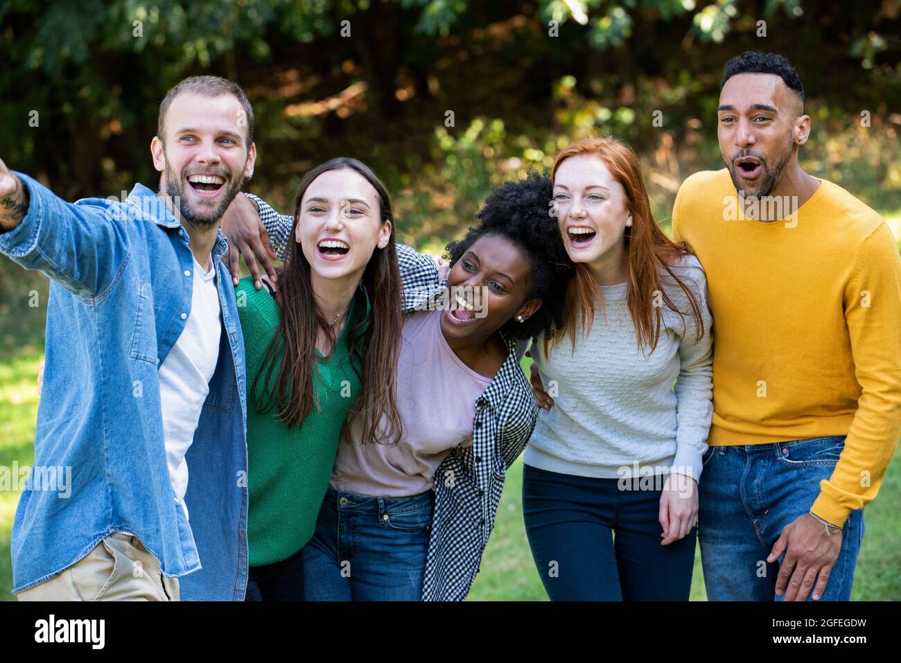 Smiling young man pointing at distance for group of friends Stock Photo ...