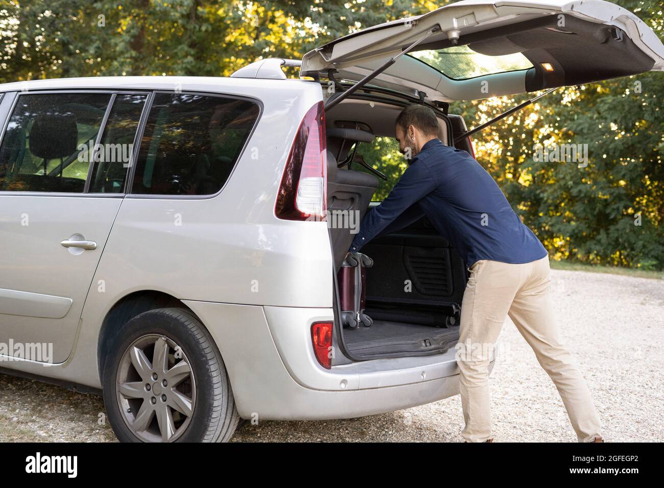 Young man loading bag in car trunk before a trip Stock Photo - Alamy