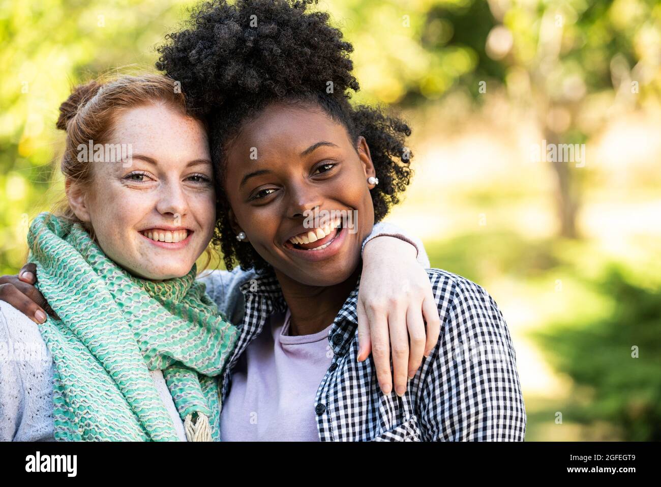 Portrait of smiling young women with arms around Stock Photo - Alamy