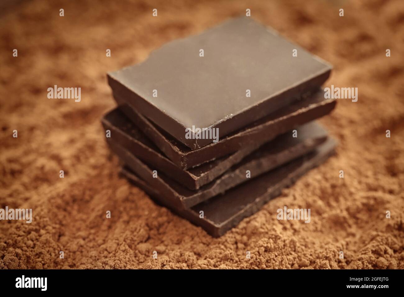 Chocolate pieces on cocoa powder background Stock Photo - Alamy