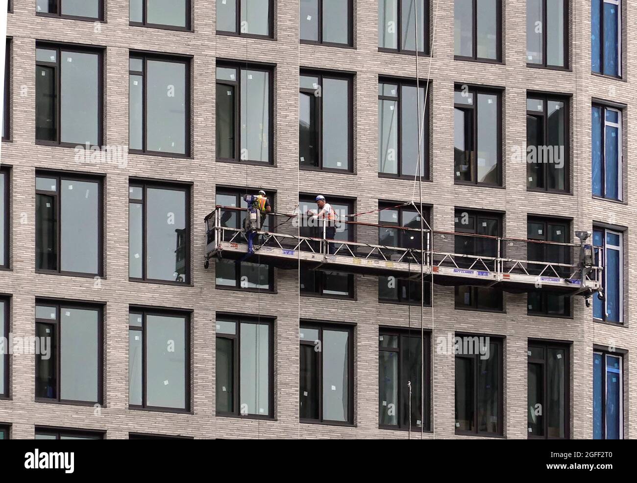 construction workers installing new windows on corporate building in ...