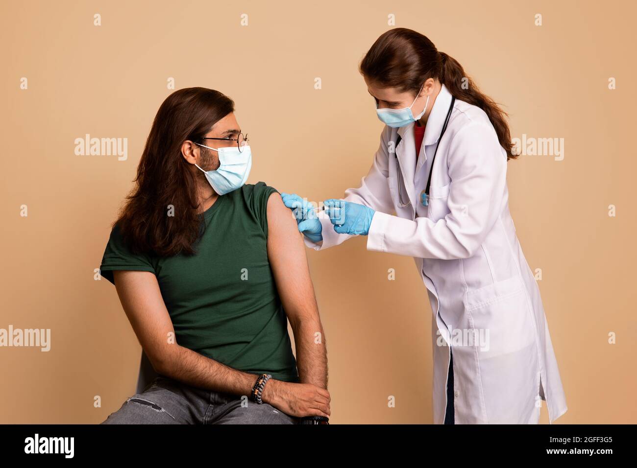 Arab guy trustfully looking at doctor making injection Stock Photo - Alamy