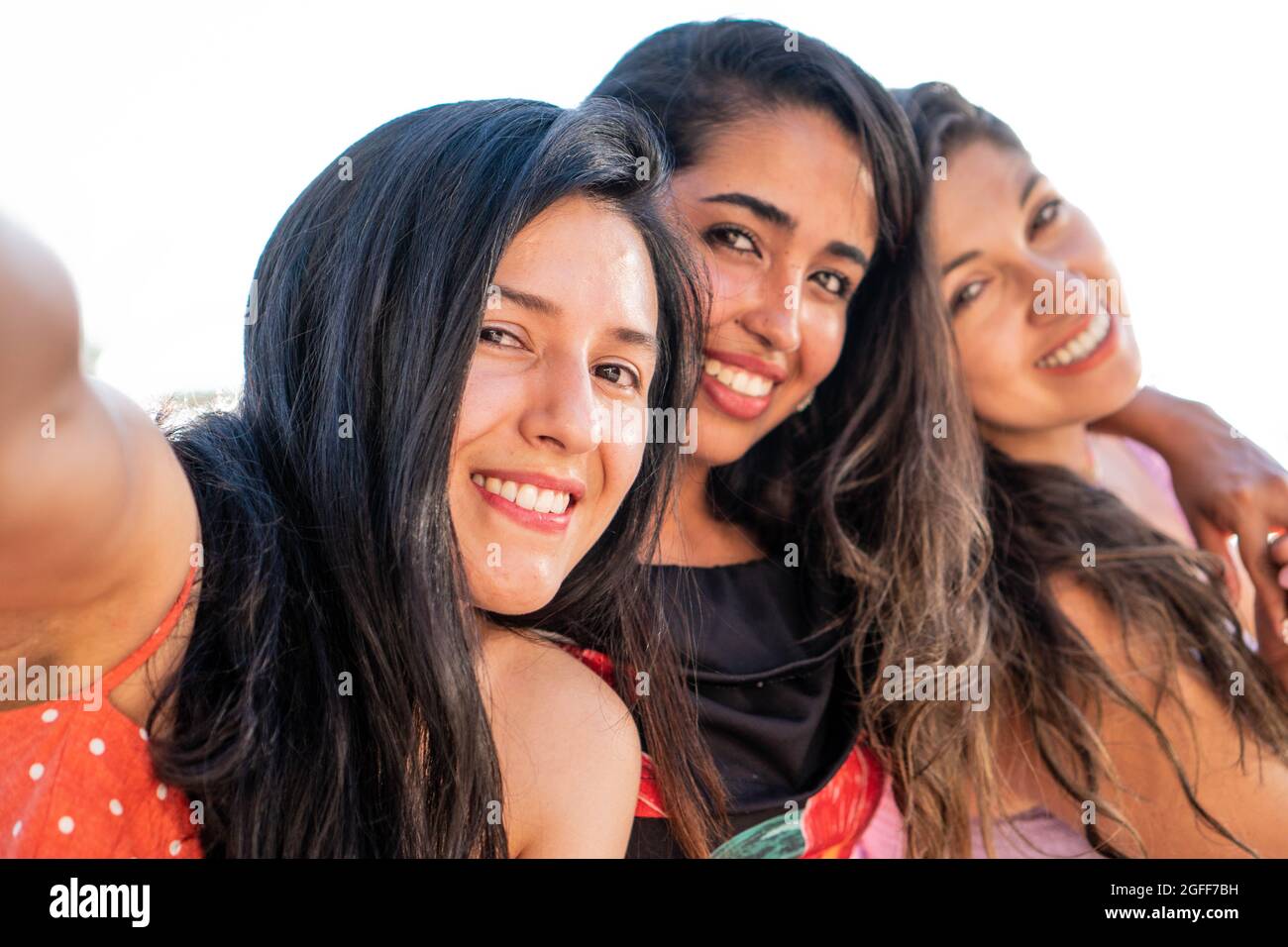 Three latin friends taking a picture of themselves outdoors in a sunny ...