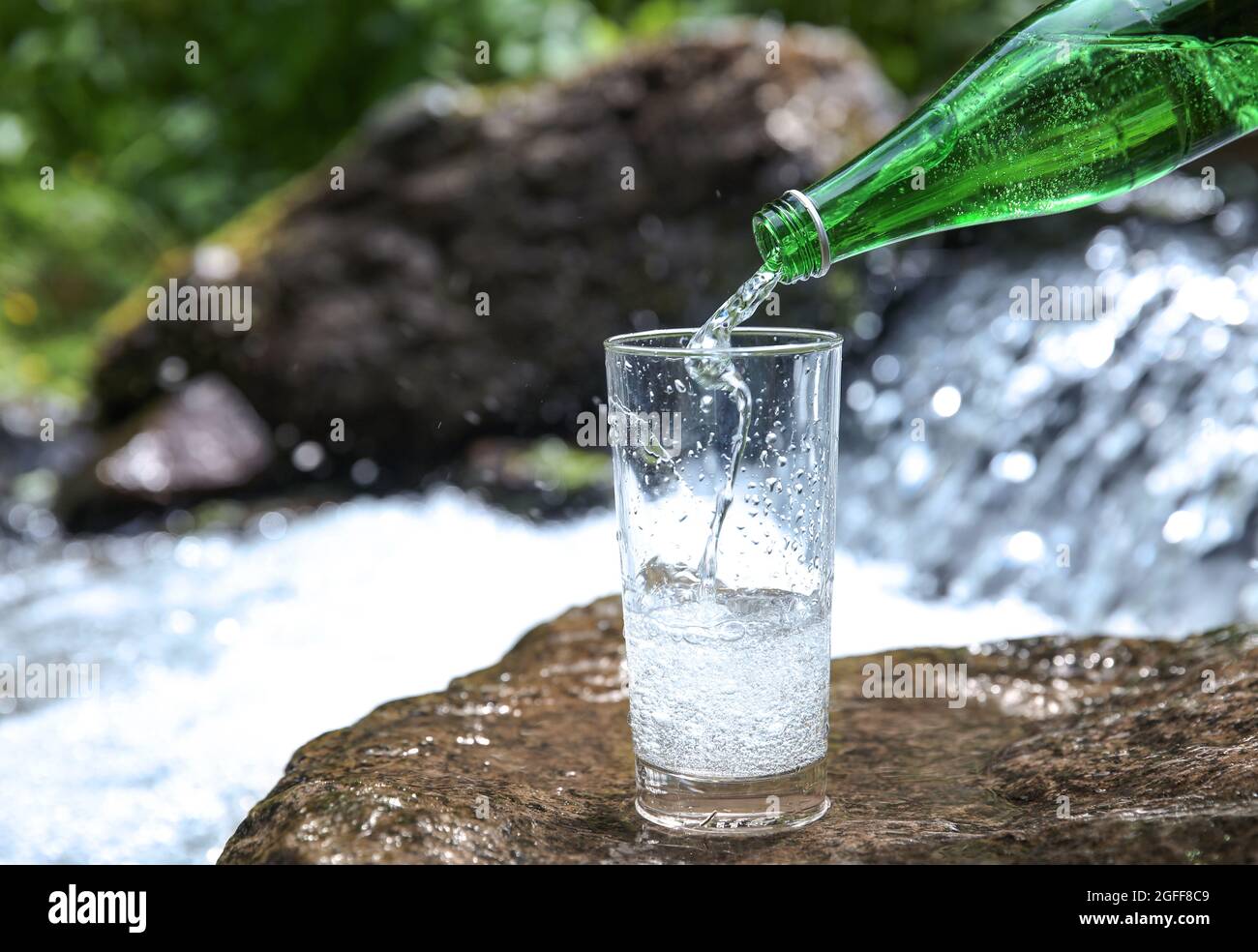 Pouring water in cup on small waterfall background Stock Photo - Alamy