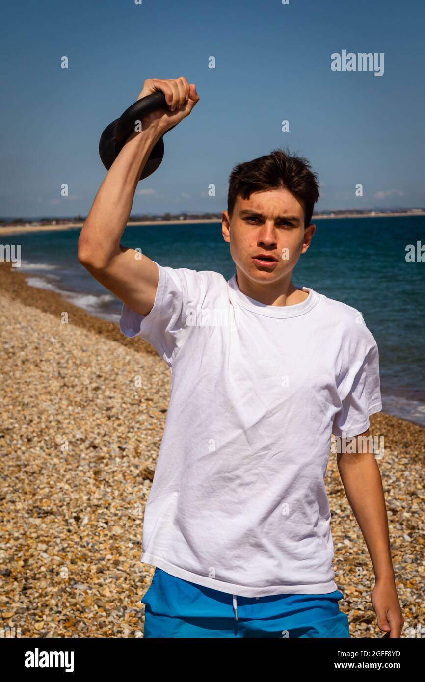 A 18 Year Old Caucasian Teenage Boy On A Beach Exercising With A a-18-year-old-caucasian-teenage-boy-on-a-beach-exercising-with-a