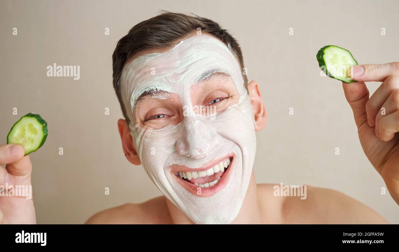 Young man with mask on face playing with cucumber rings closing eyes ...